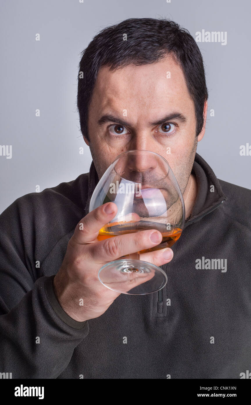 Handsome man sniffing a glass of whiskey Stock Photo - Alamy