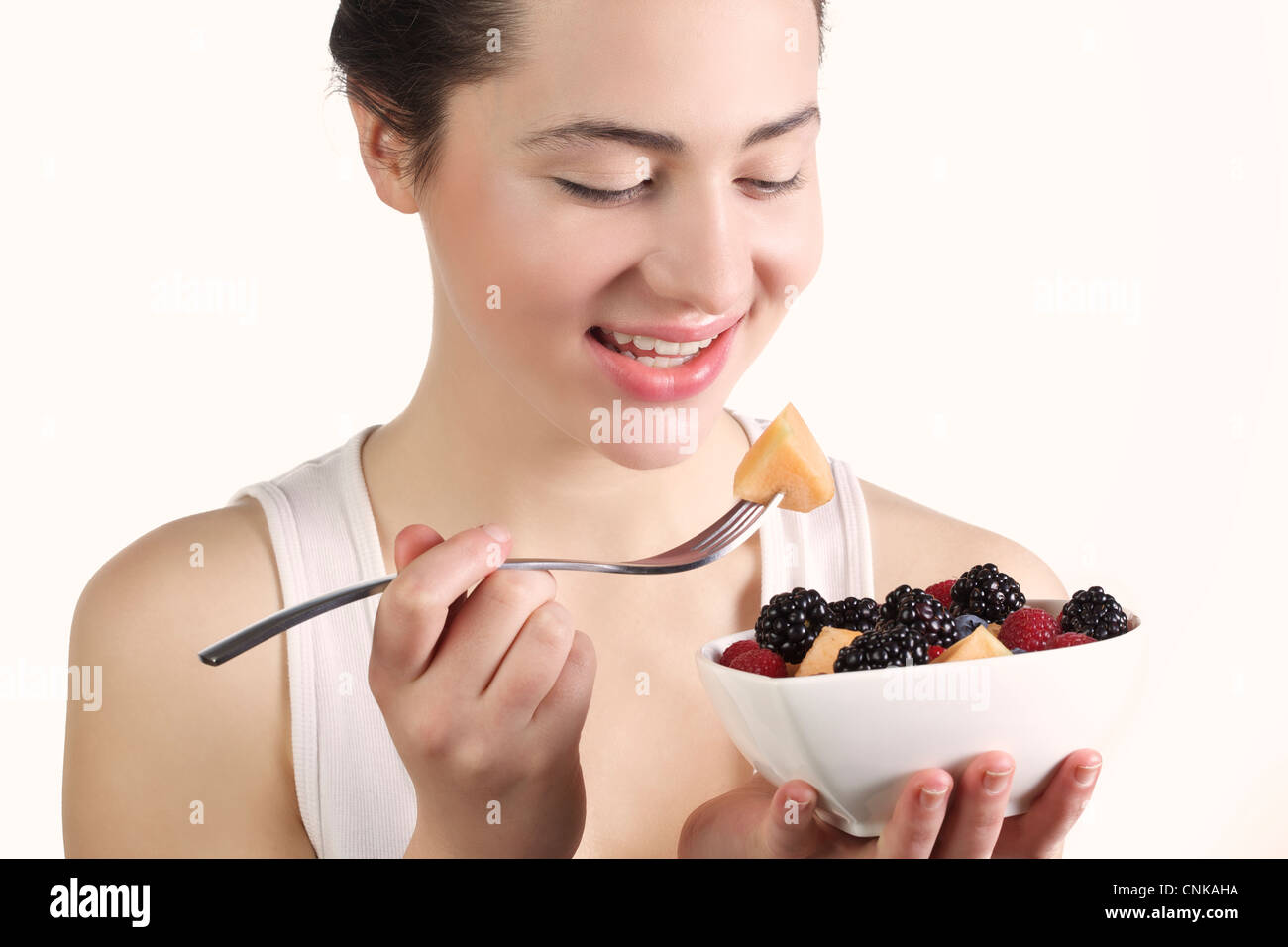 Beautiful young woman eating fruit salad Stock Photo - Alamy