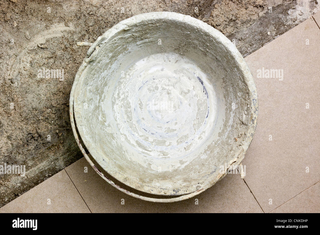 Grungy bucket on unfinished flooring showing the tiles and concrete ...