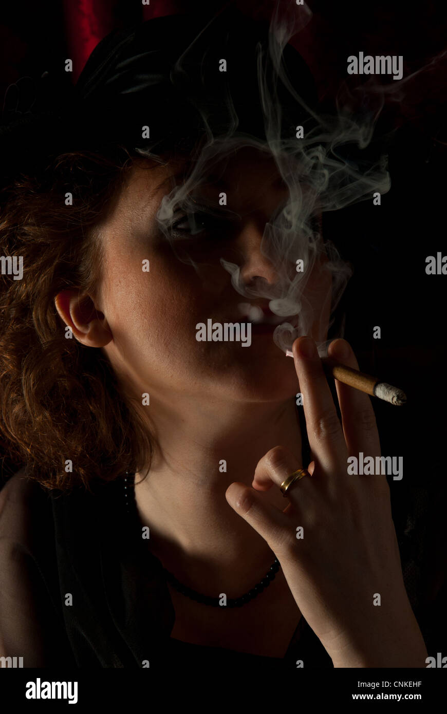 Smoking elegant woman with hat in night Stock Photo - Alamy