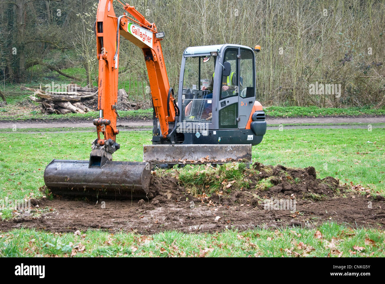 A mechanical digger preparing ground for the sowing of wild flowers ...