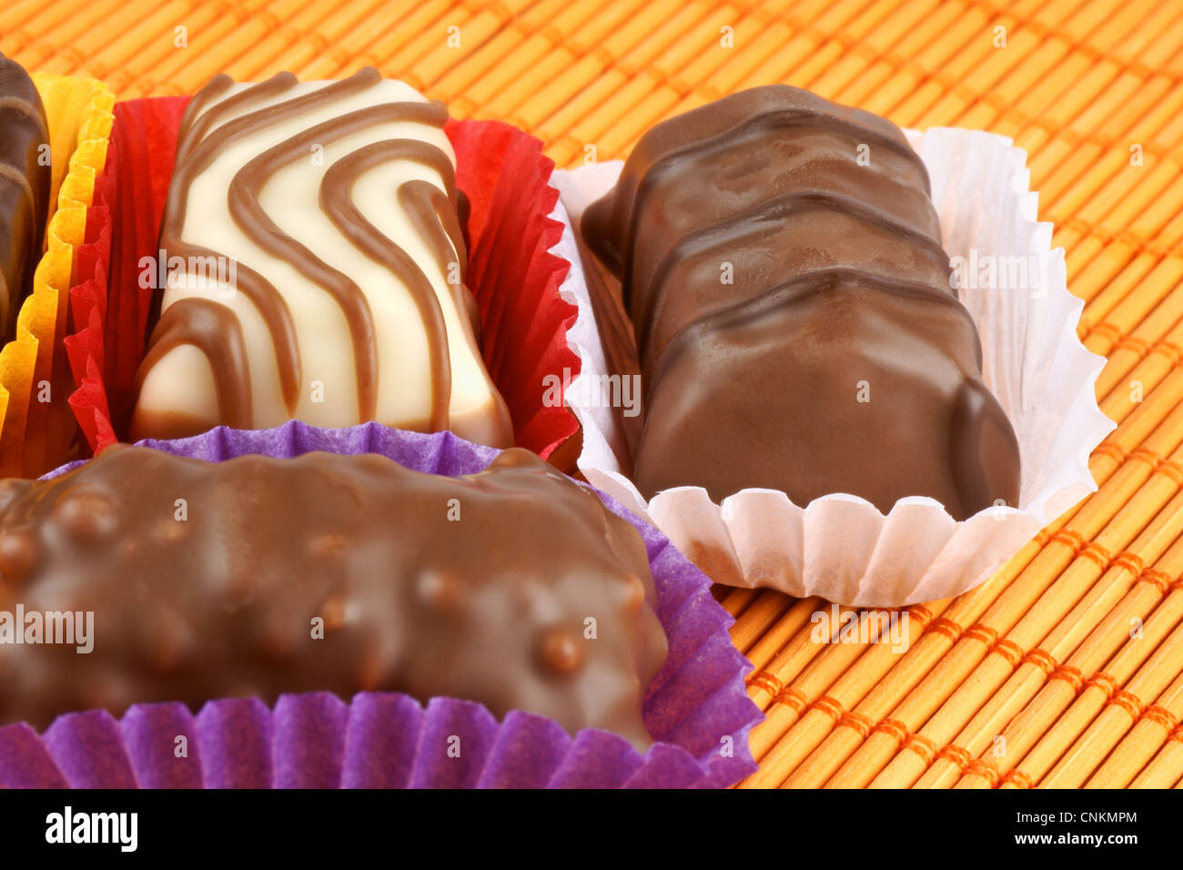 Closeup of some mixed chocolate pralines over an orange background ...