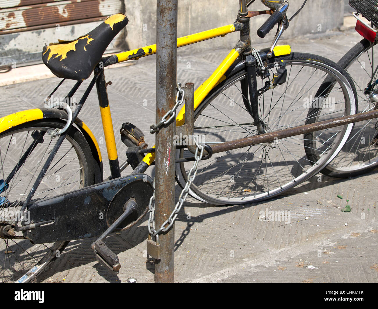 old yellow crashed bike locked by chain Stock Photo - Alamy