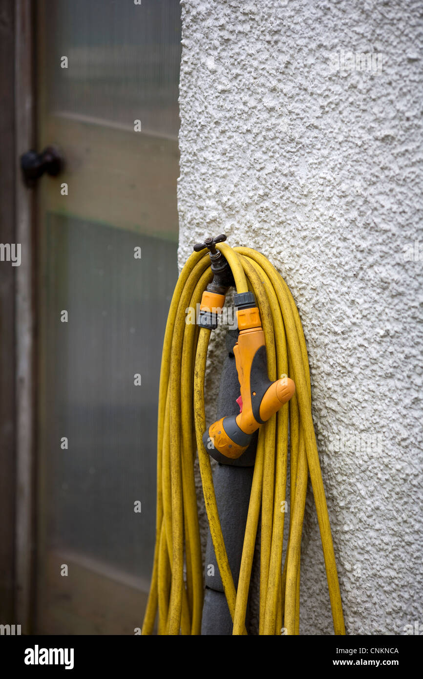 Yellow hose wrapped around tap Stock Photo - Alamy