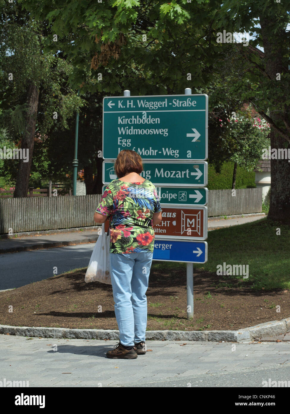A female tourist gazing at a road sign in Kirchboden for directions to ...