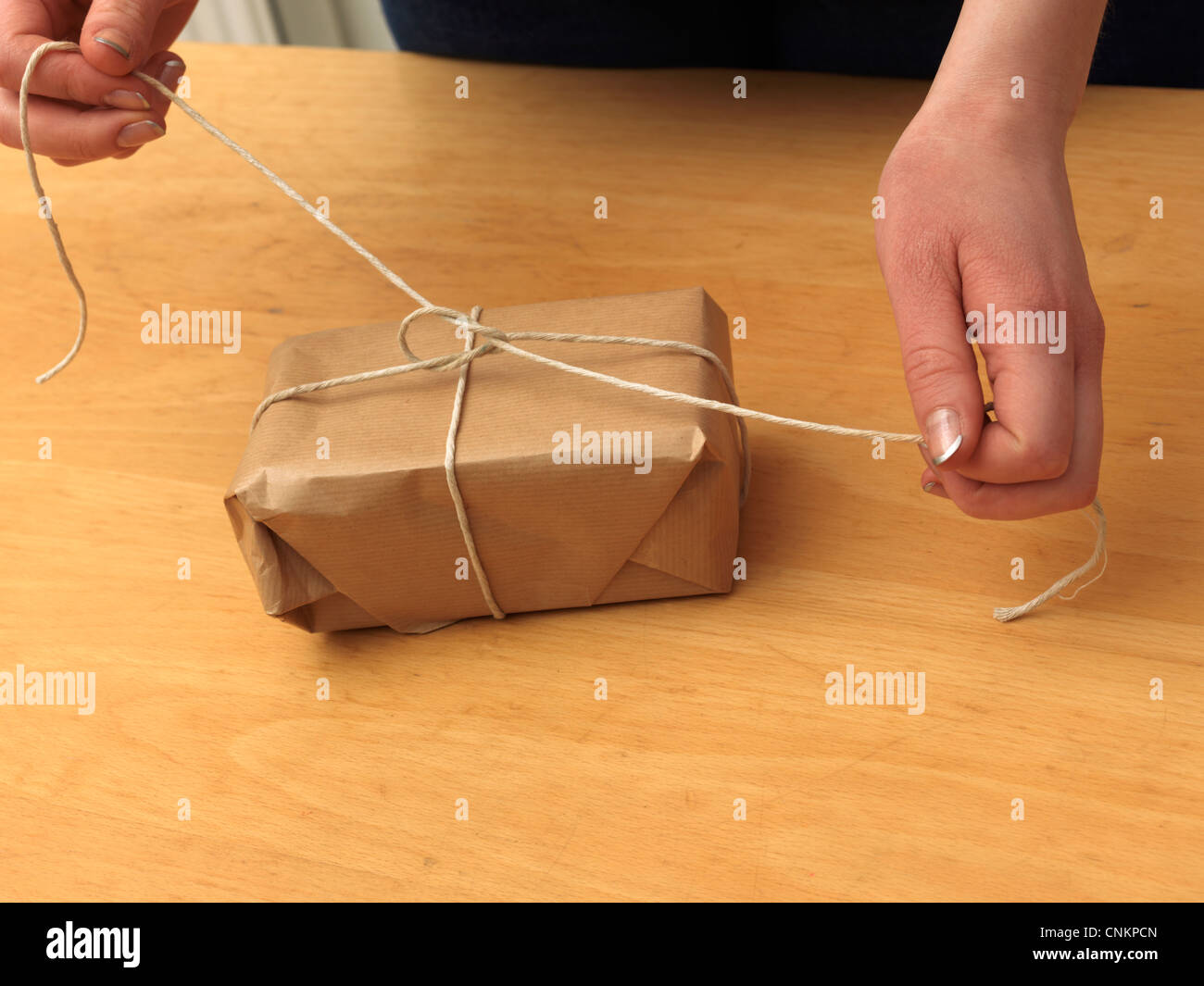 Tying Knot In String Around A Parcel Stock Photo - Alamy