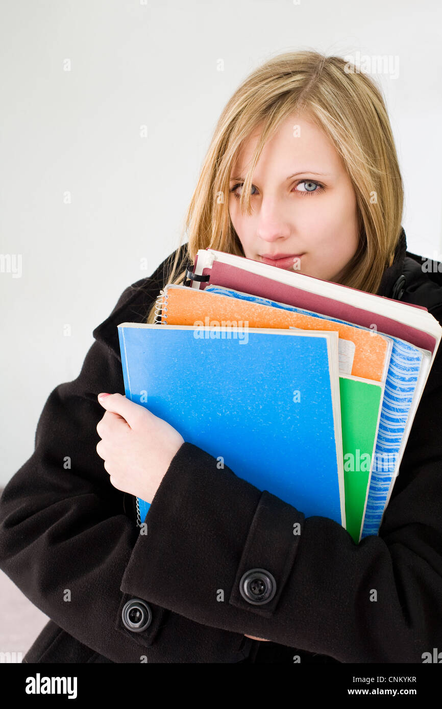Outdoors portrait of a cute blond student girl holding exercise books ...