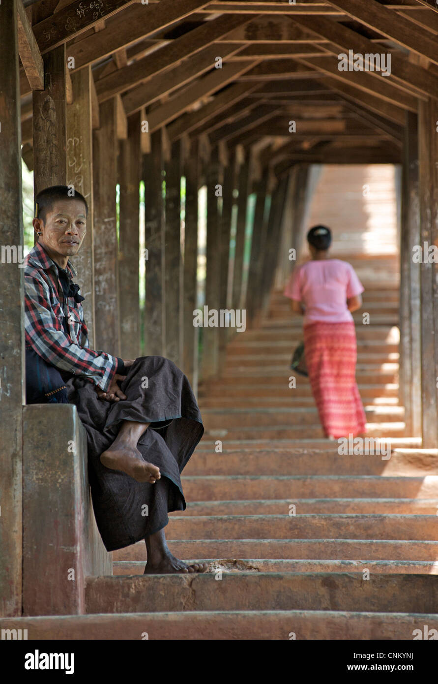 Burmese man with thanaka painted face on the covered walkway steps to ...