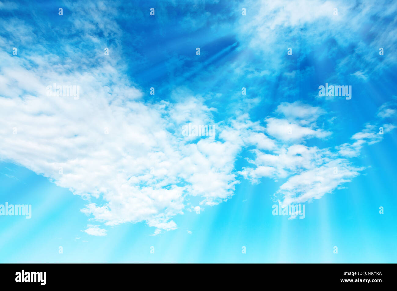 Sun rays through soft spring clouds on a blue sky shot with wide lens ...