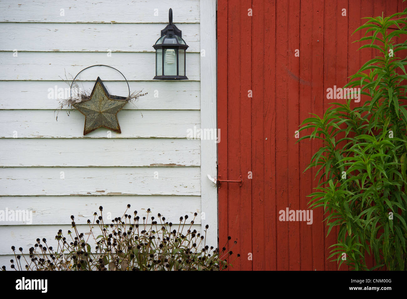 Star decoration and lamp on the side of a white barn with a red door ...
