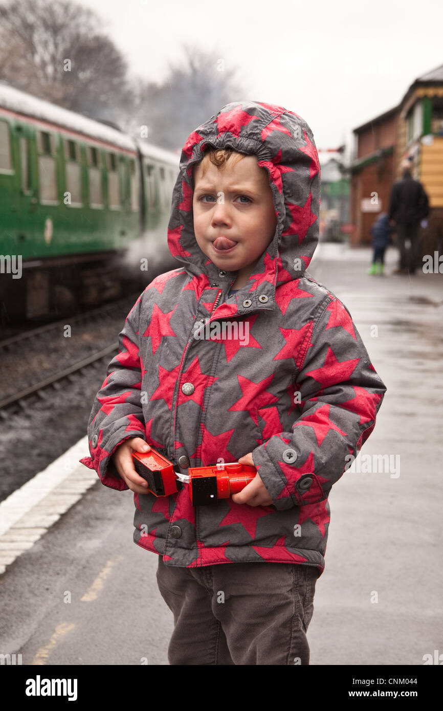 Young boy (3 years old) watching the steam trains in the rain. Ropley ...