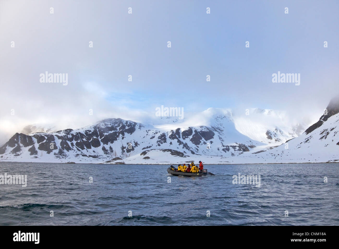 Arctic tourists in zodiac inflatable boat exploring the landscape in ...