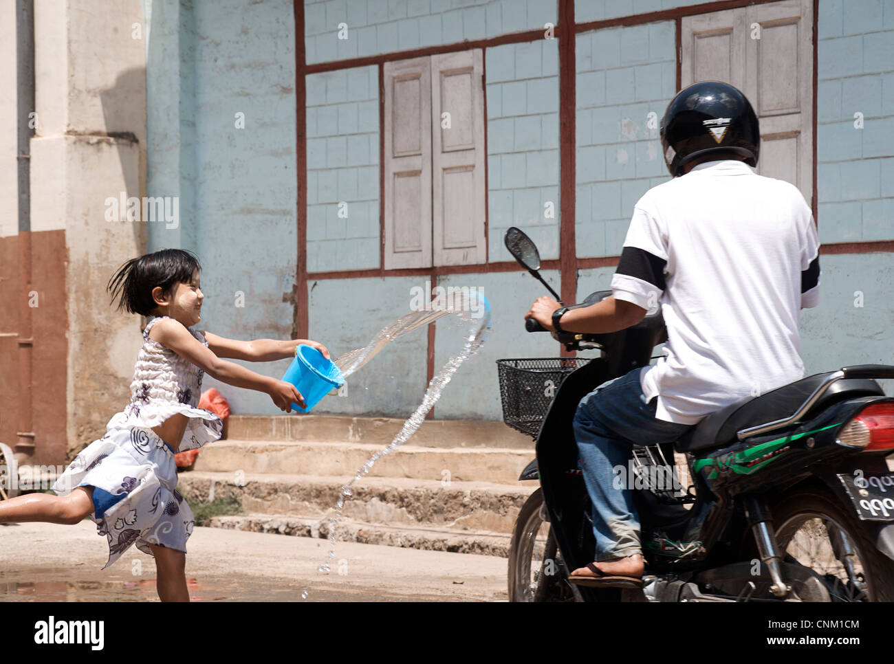 Burmese girl enjoying the water festival by throwing a bucket of water ...
