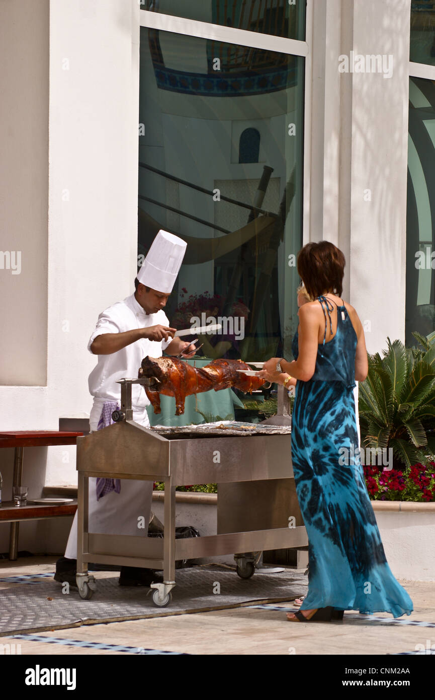 Woman in blue dress served with roast pig by a chef Friday brunch at ...
