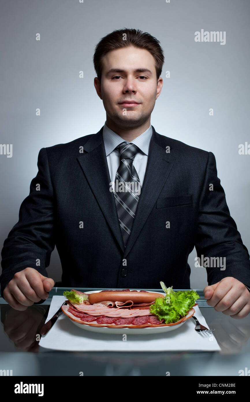 Young businessman eating. Rich meat menu Stock Photo - Alamy