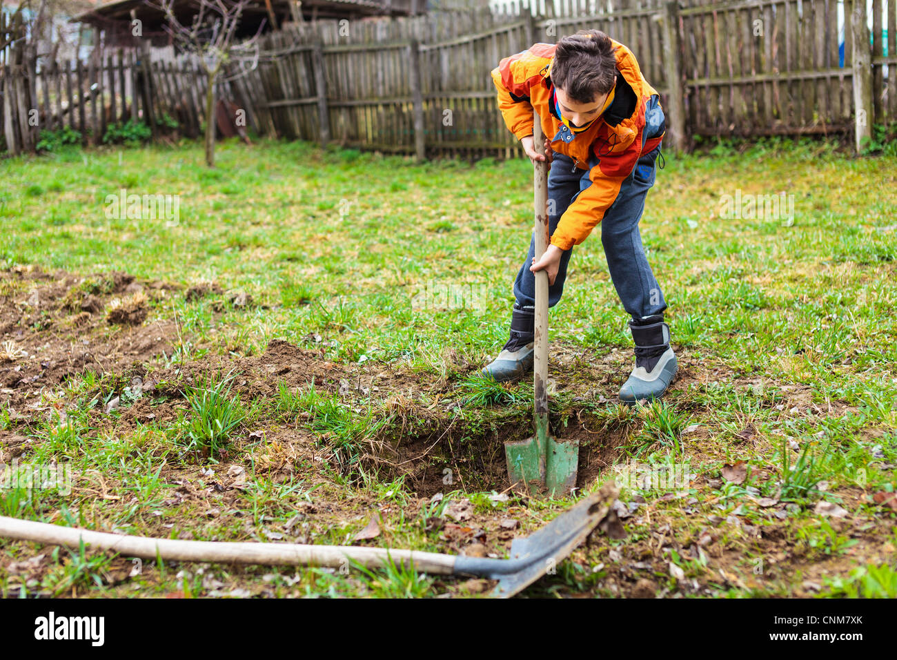 Boy digging on a grass field in the countryside Stock Photo - Alamy
