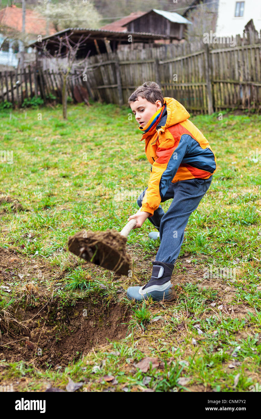 Boy digging on a grass field in the countryside Stock Photo - Alamy