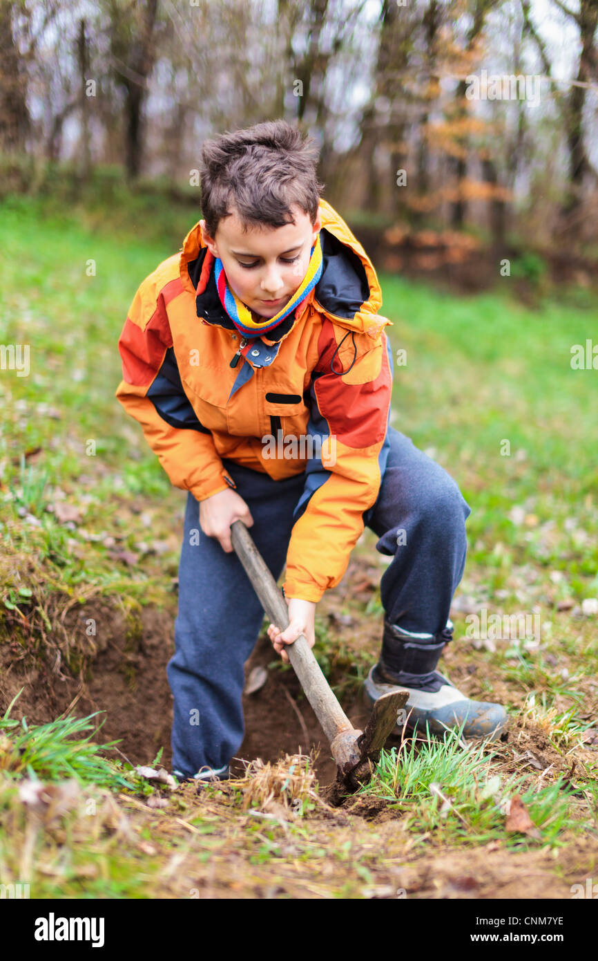 Boy digging on a grass field in the countryside Stock Photo - Alamy