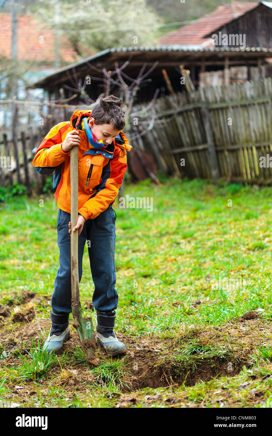 Boy digging on a grass field in the countryside Stock Photo - Alamy