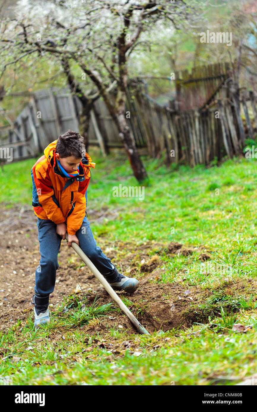 Boy digging on a grass field in the countryside Stock Photo - Alamy