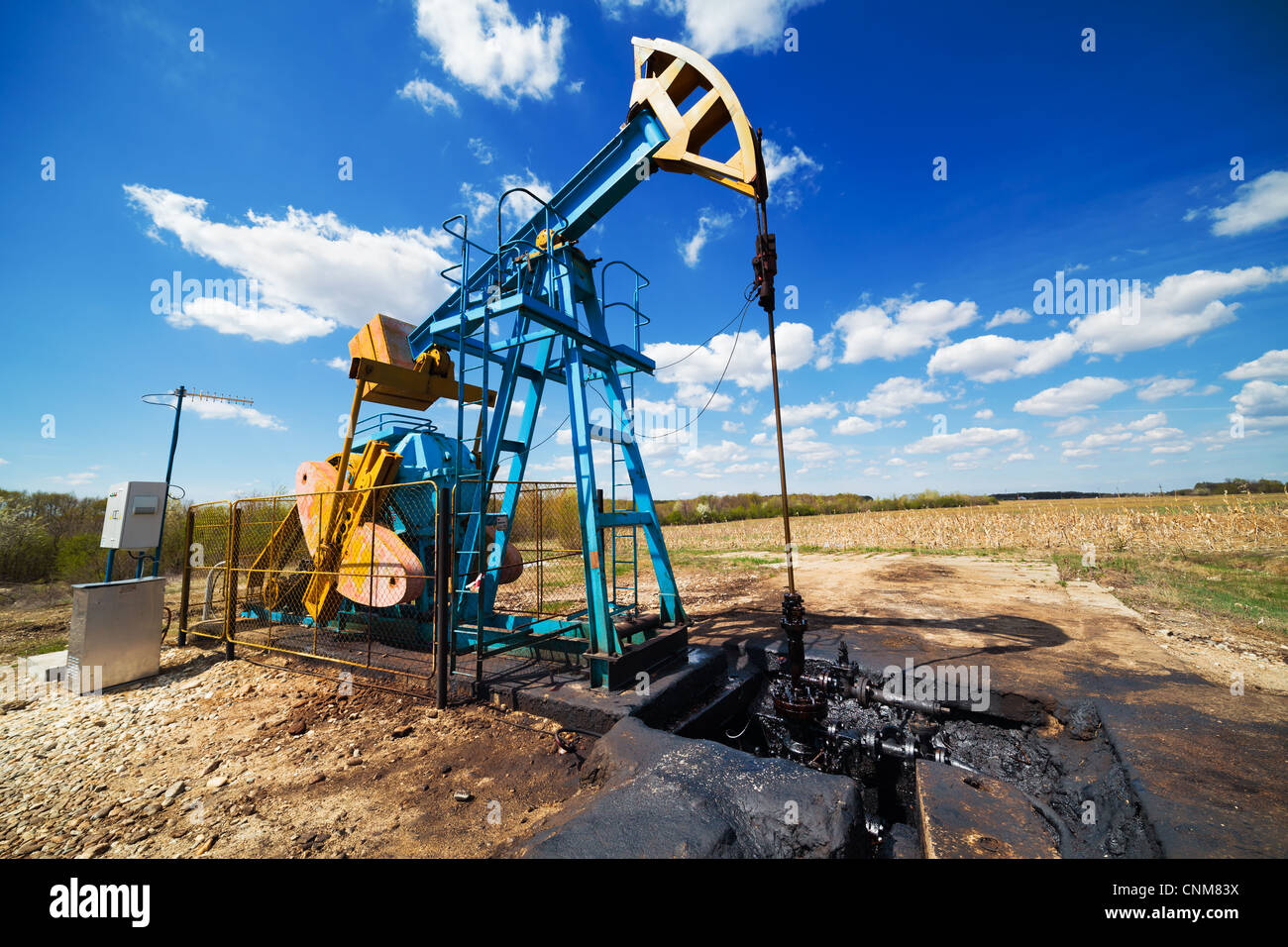 Landscape with oil pump under blue sky with clouds in a sunny day Stock Photo - Alamy