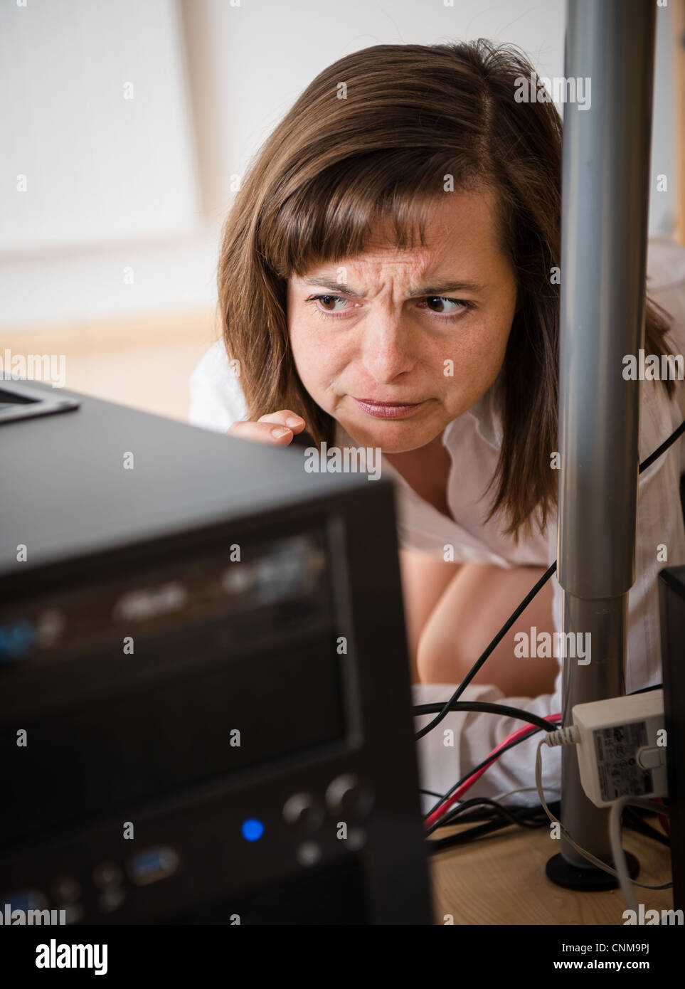Young business woman trying to repair computer under table Stock Photo ...
