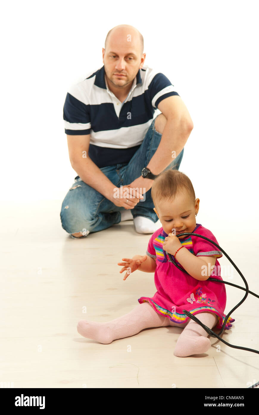 Father watching his baby girl playing with cables on floor Stock Photo ...