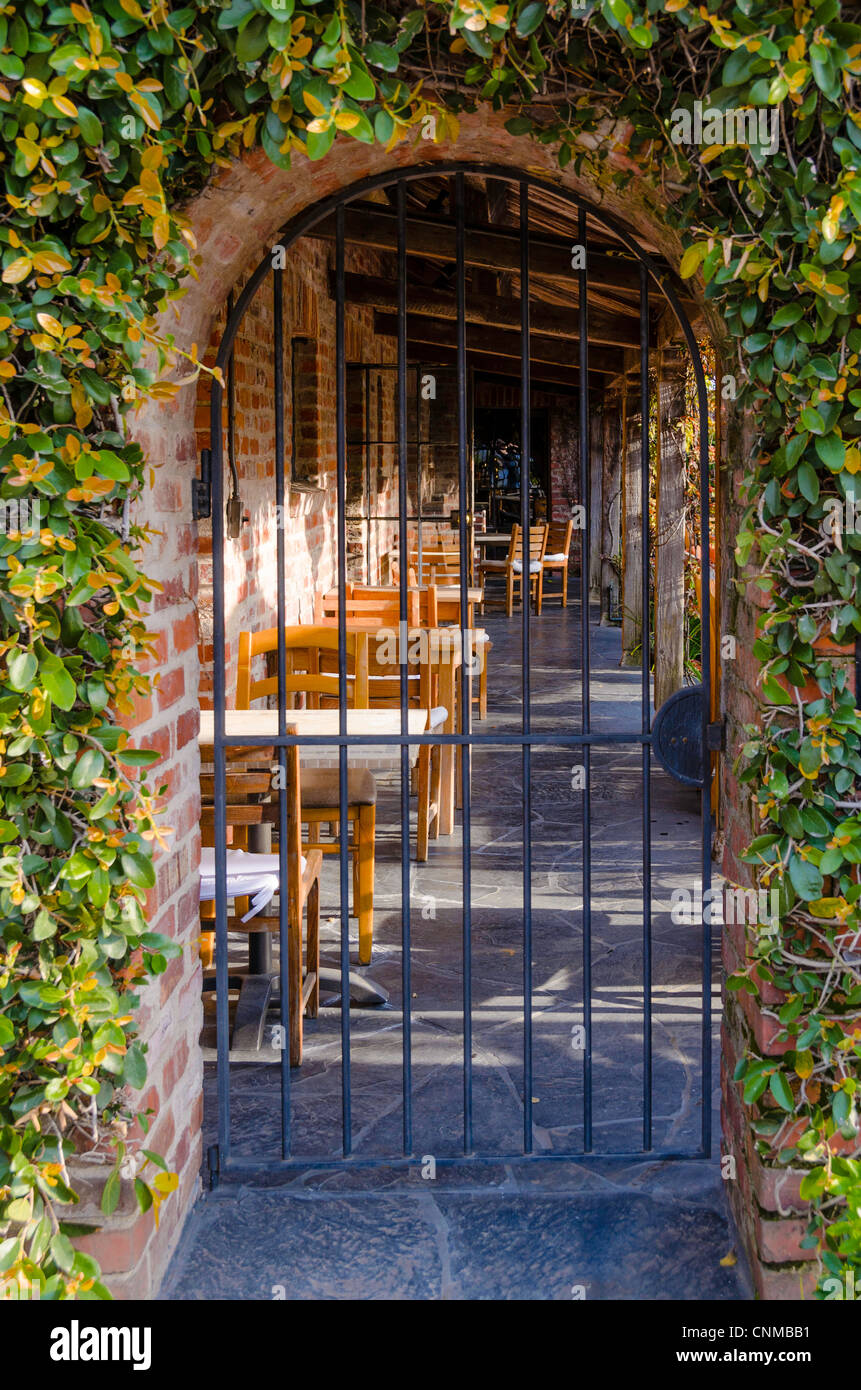 Gated, brick archway looking onto a patio Stock Photo - Alamy