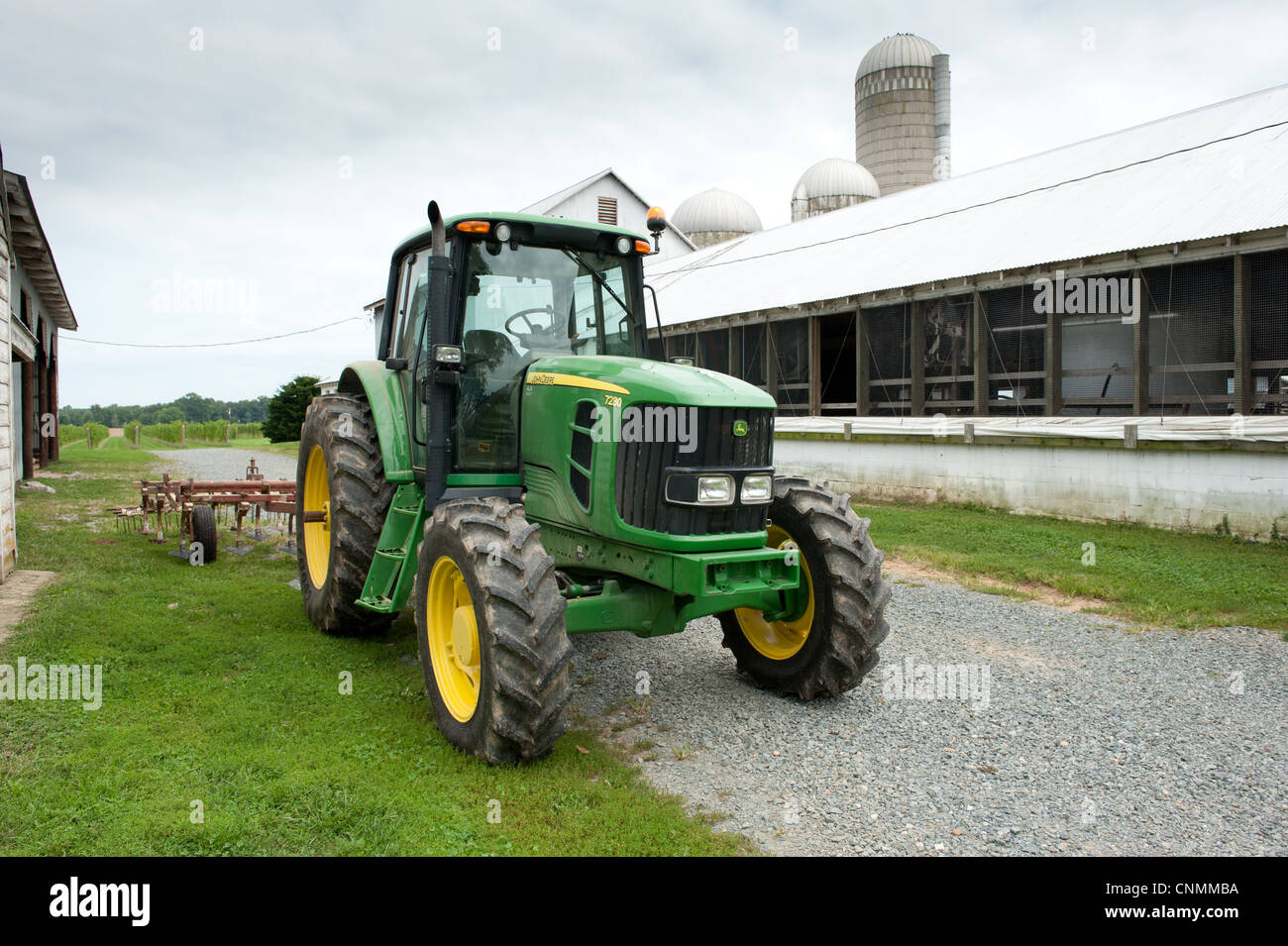 Tractor with tillage equipment attached parked outside of a barn with ...