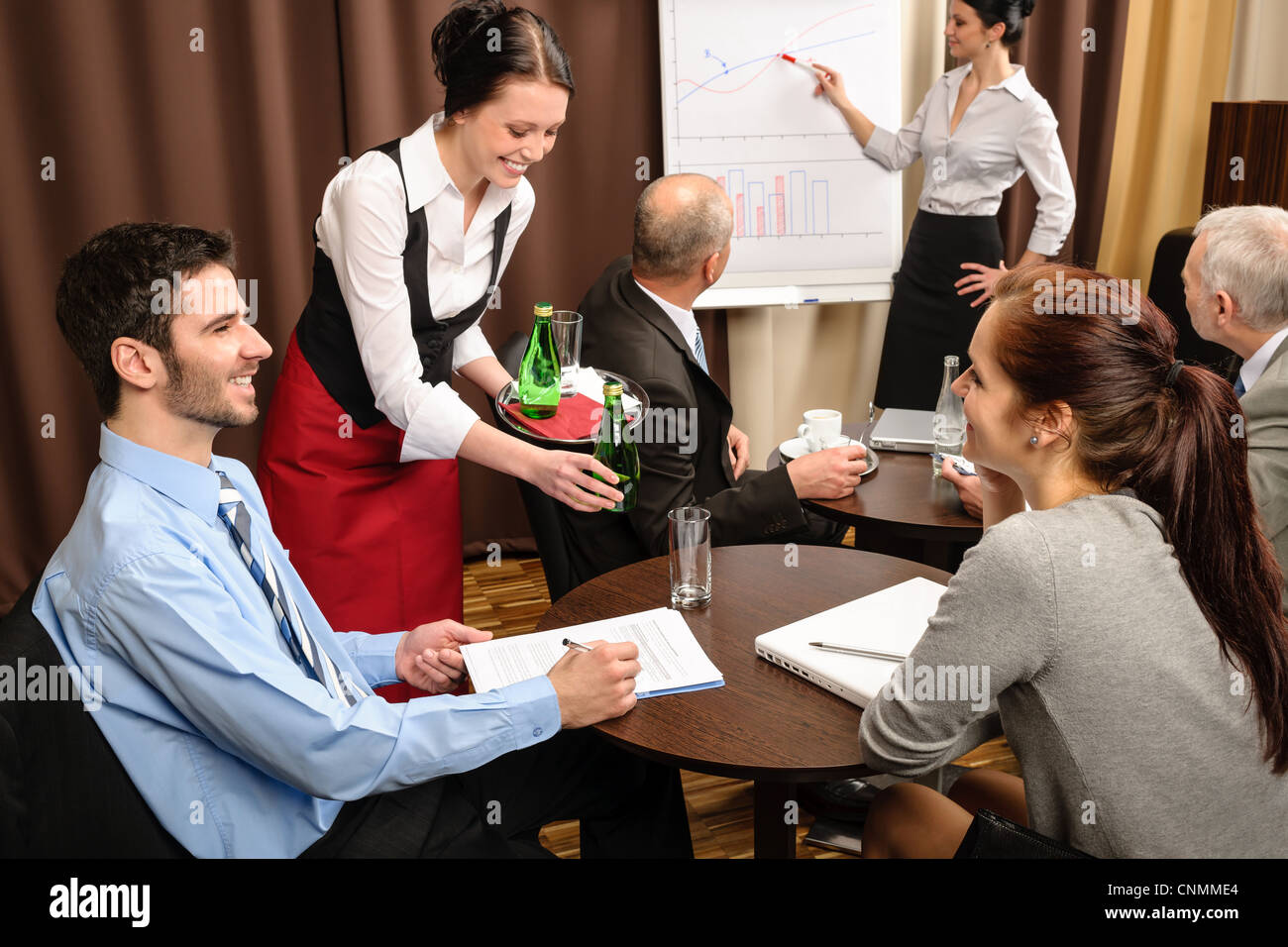 Waitress serving people at business meeting flipchart presentation ...
