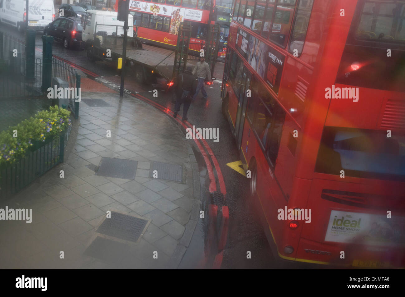 Aerial view through misted bus window of red buses below during ...