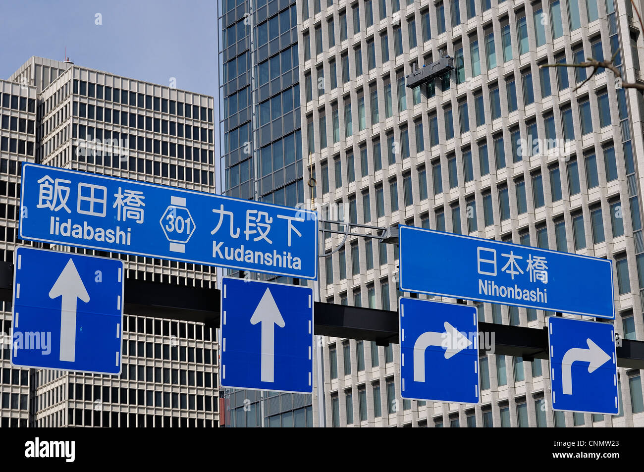 Blue/white road signs over major road with skyscrapers in the ...