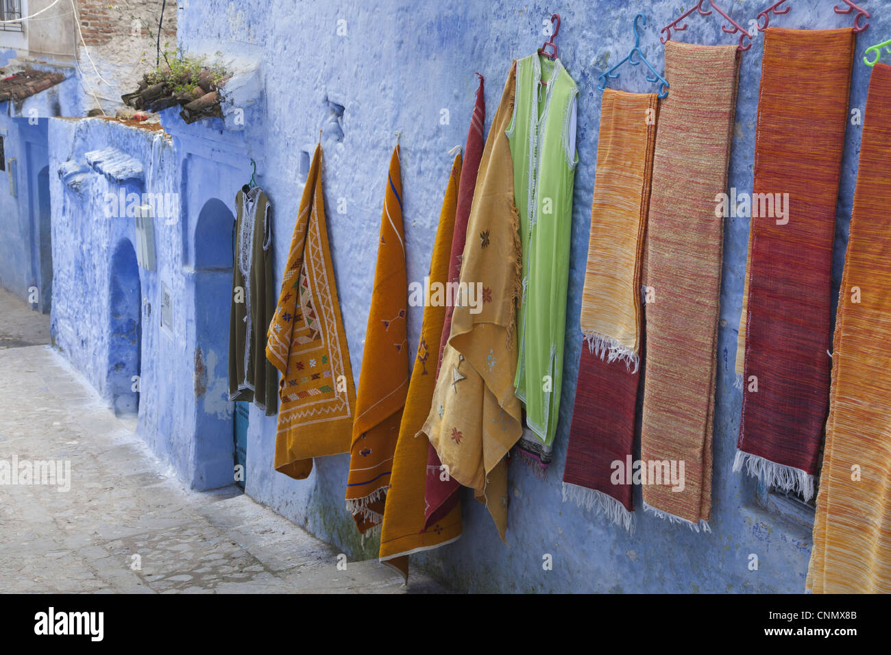 Blue houses and textiles for sale in alley of city, Chefchaouen ...
