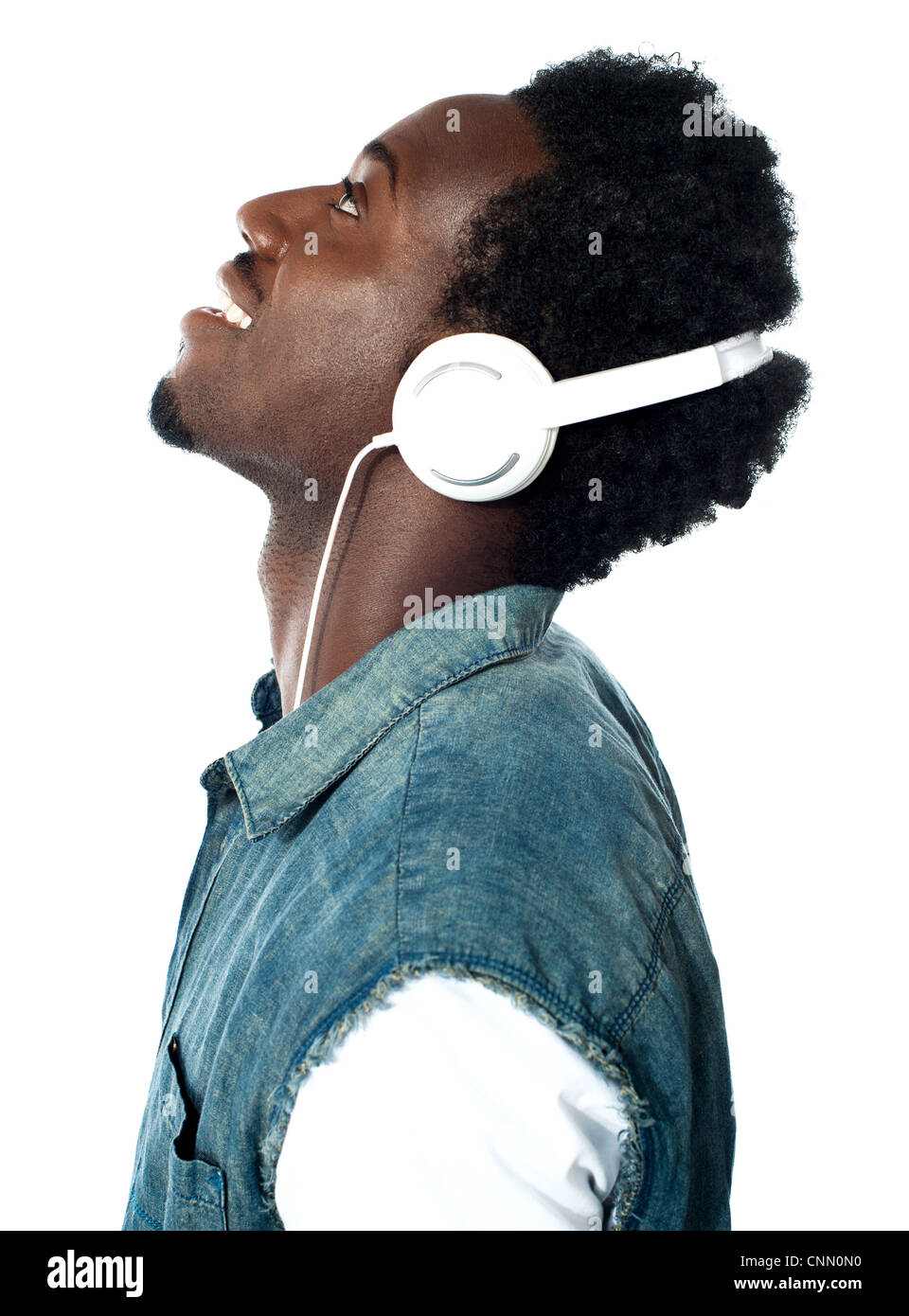 A handsome young boy listening to music on his mp3 player, looking up ...