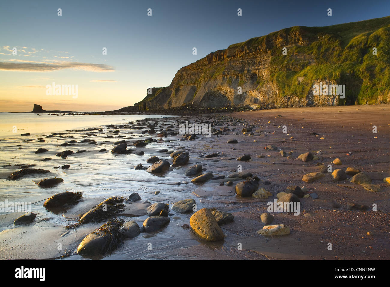 Rocks on sandy beach with sea cliffs at sunrise, Black Nab, Saltwick ...