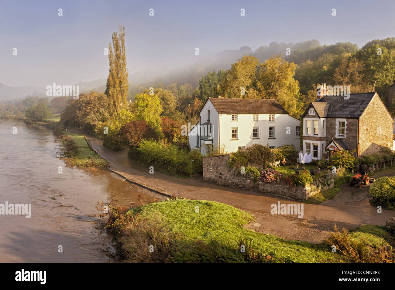 View of village on riverbank in mist at dawn, Brockweir, River Wye ...