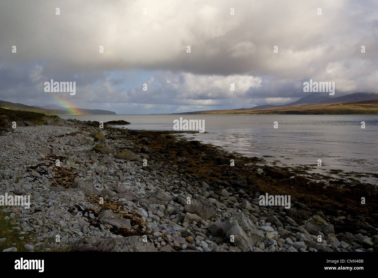 View of rainclouds and rainbow over coastal strait Islay Sound, Islay ...