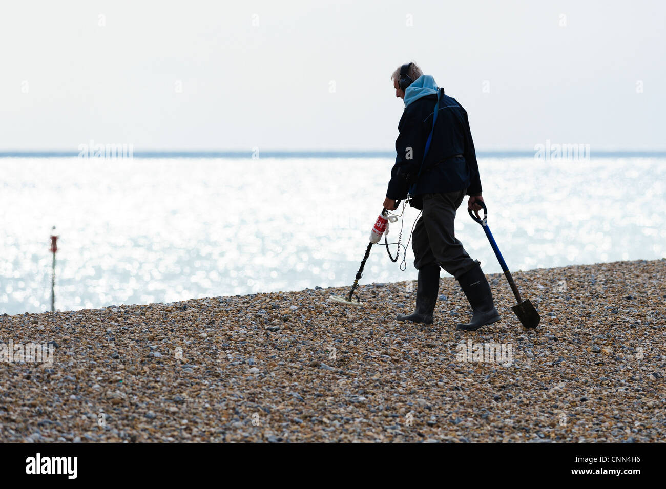 Man using a metal detector on a beach in the Uk Stock Photo - Alamy