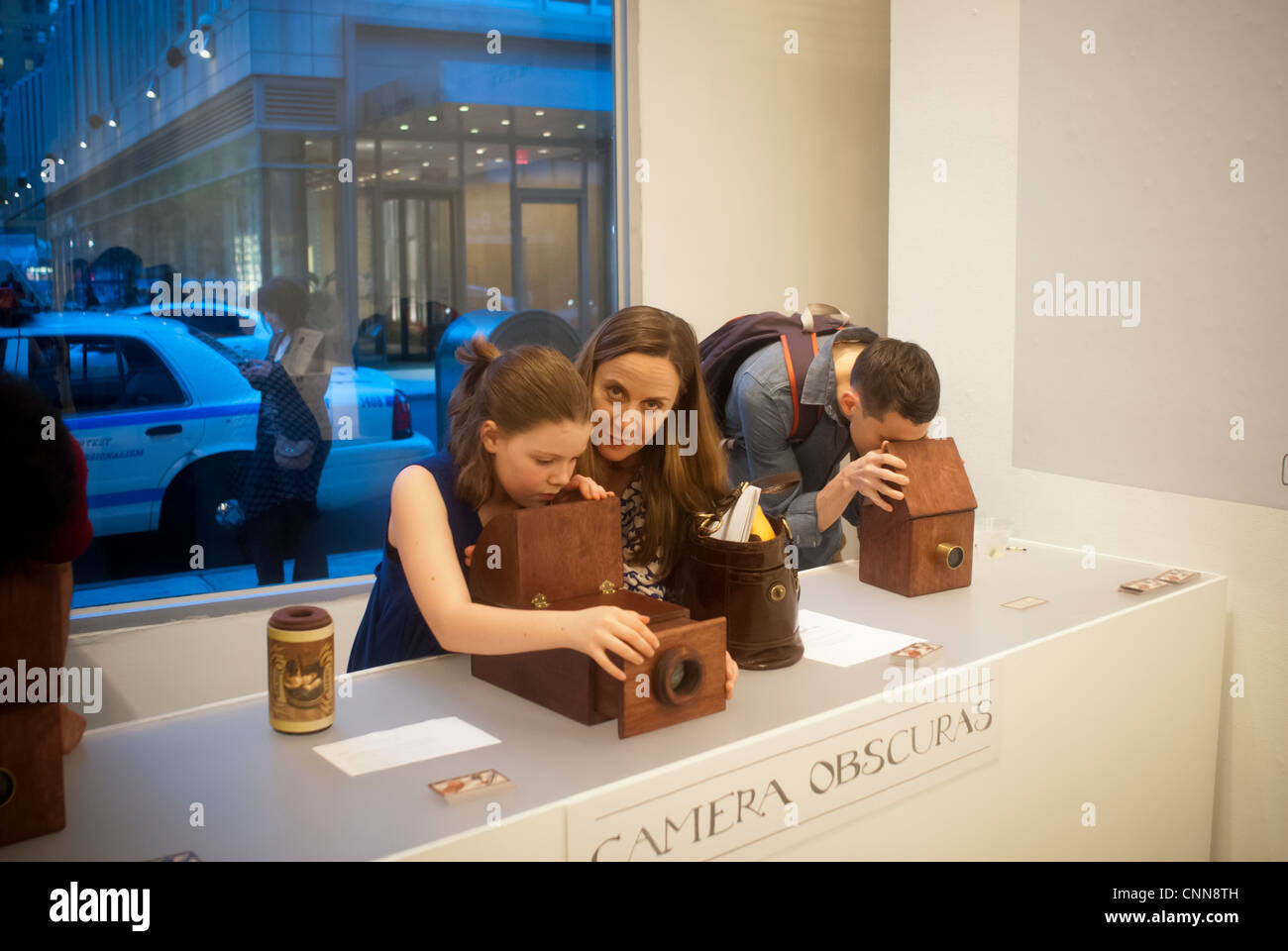 Visitors to a gallery in New York use camera obscura devices on display ...