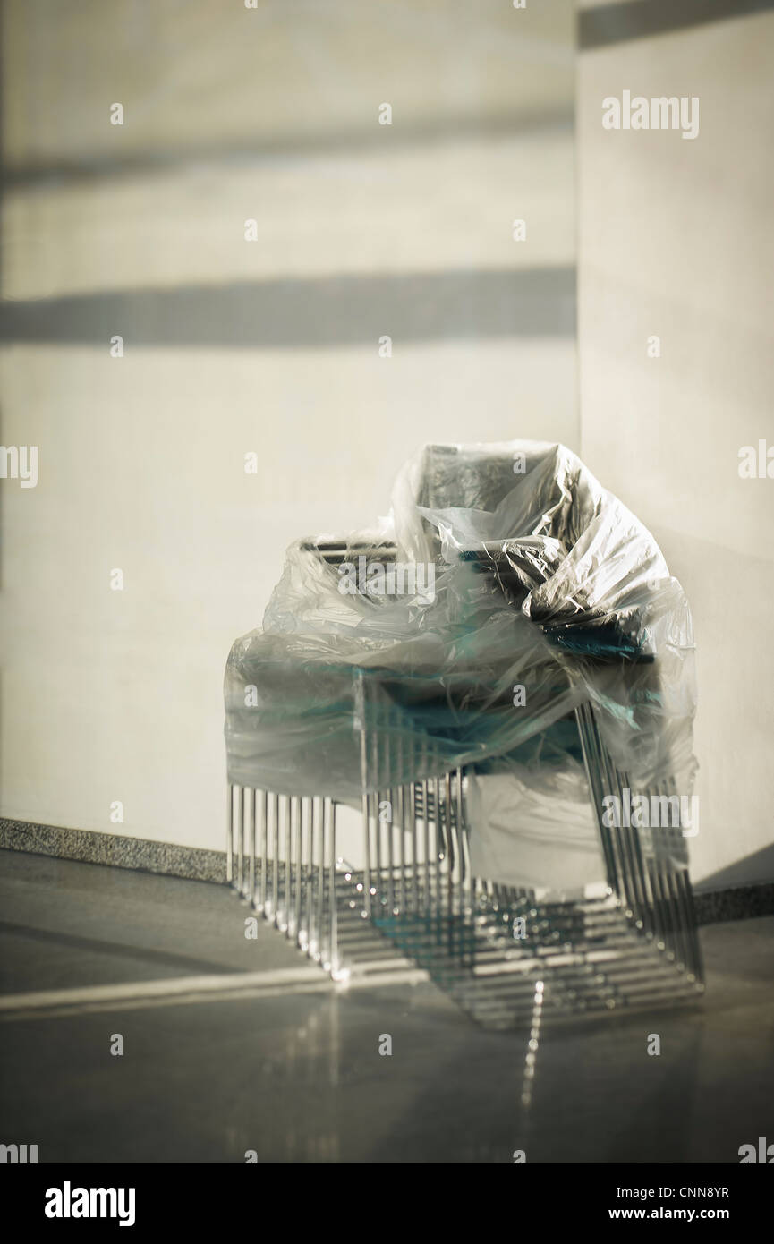 Stack of plastic wrapped office chairs in empty building ready for ...