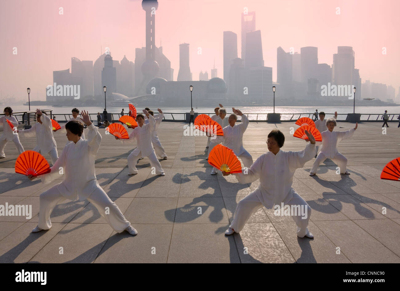 People practicing Taiji with red fans on the Bund, Pudong skyline in ...