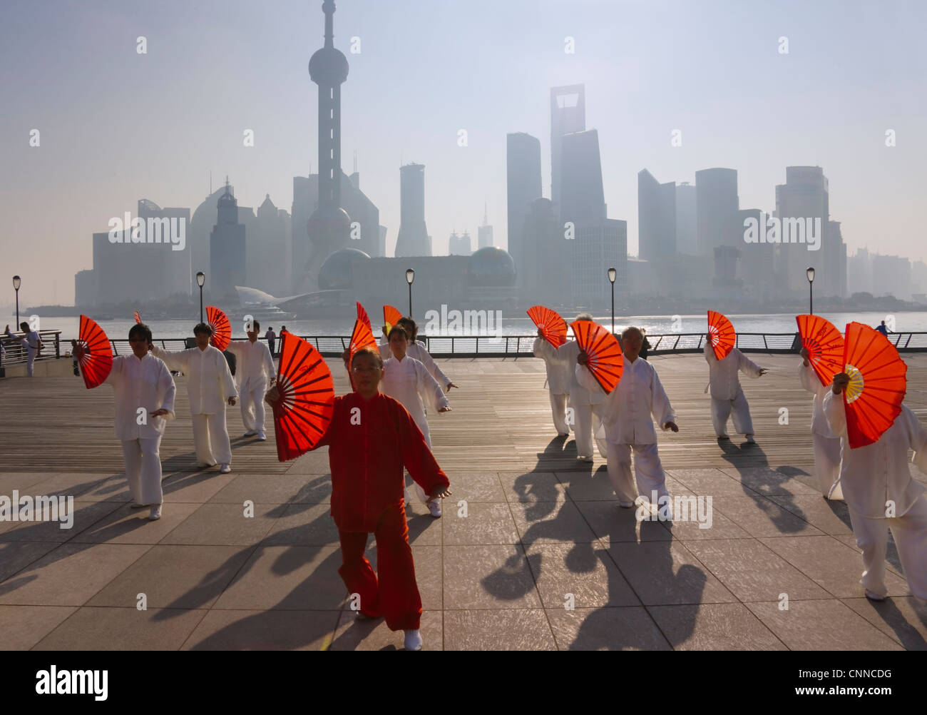 People practicing Taiji with red fans on the Bund, Pudong skyline in ...