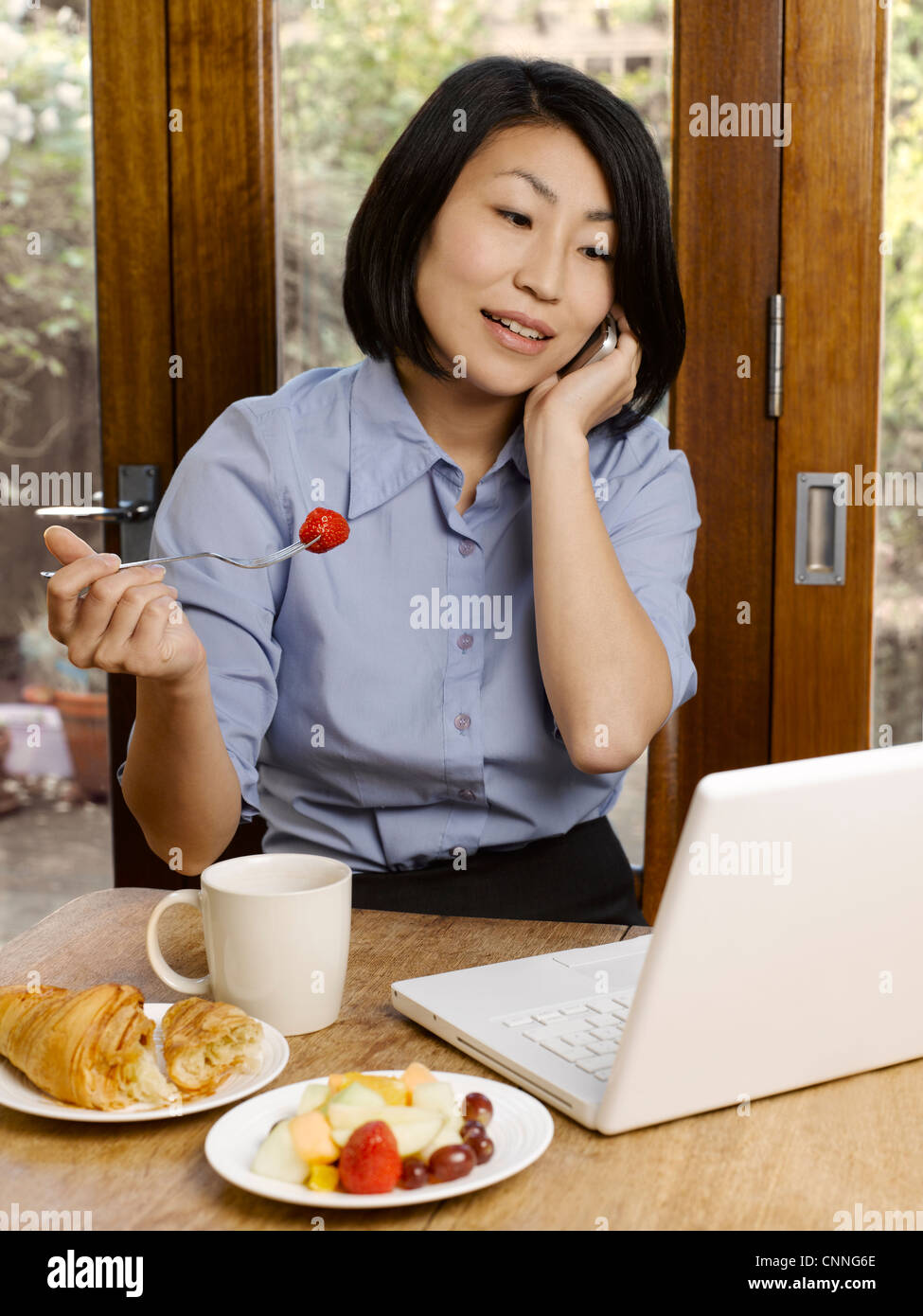 Businesswoman eating and working Stock Photo - Alamy