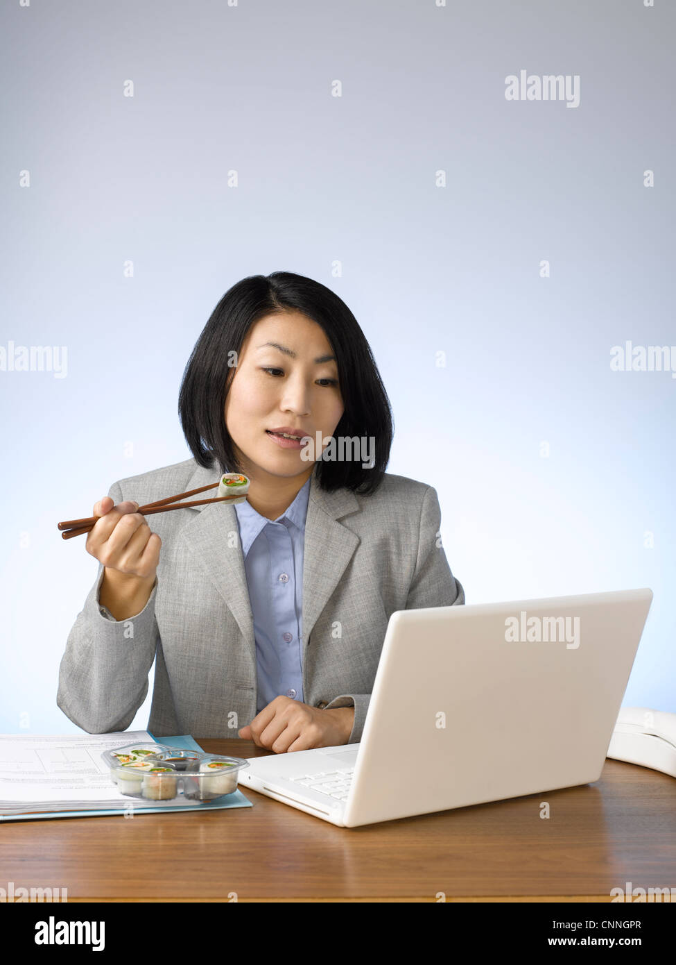 Businesswoman eating and working at desk Stock Photo - Alamy