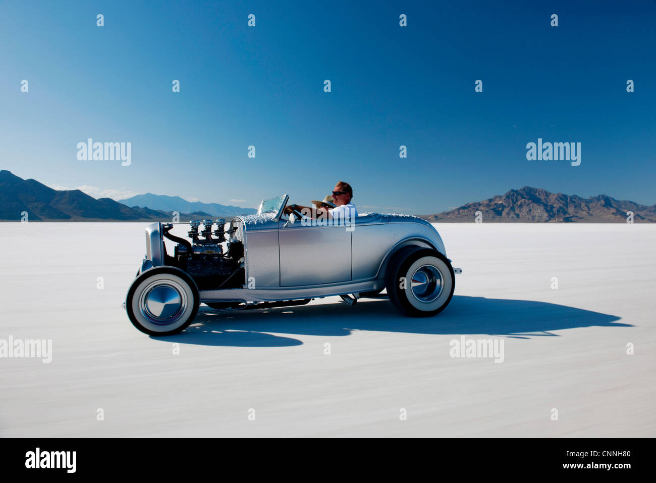 retro car driving across bonneville salt flats US blue sky white sand ...