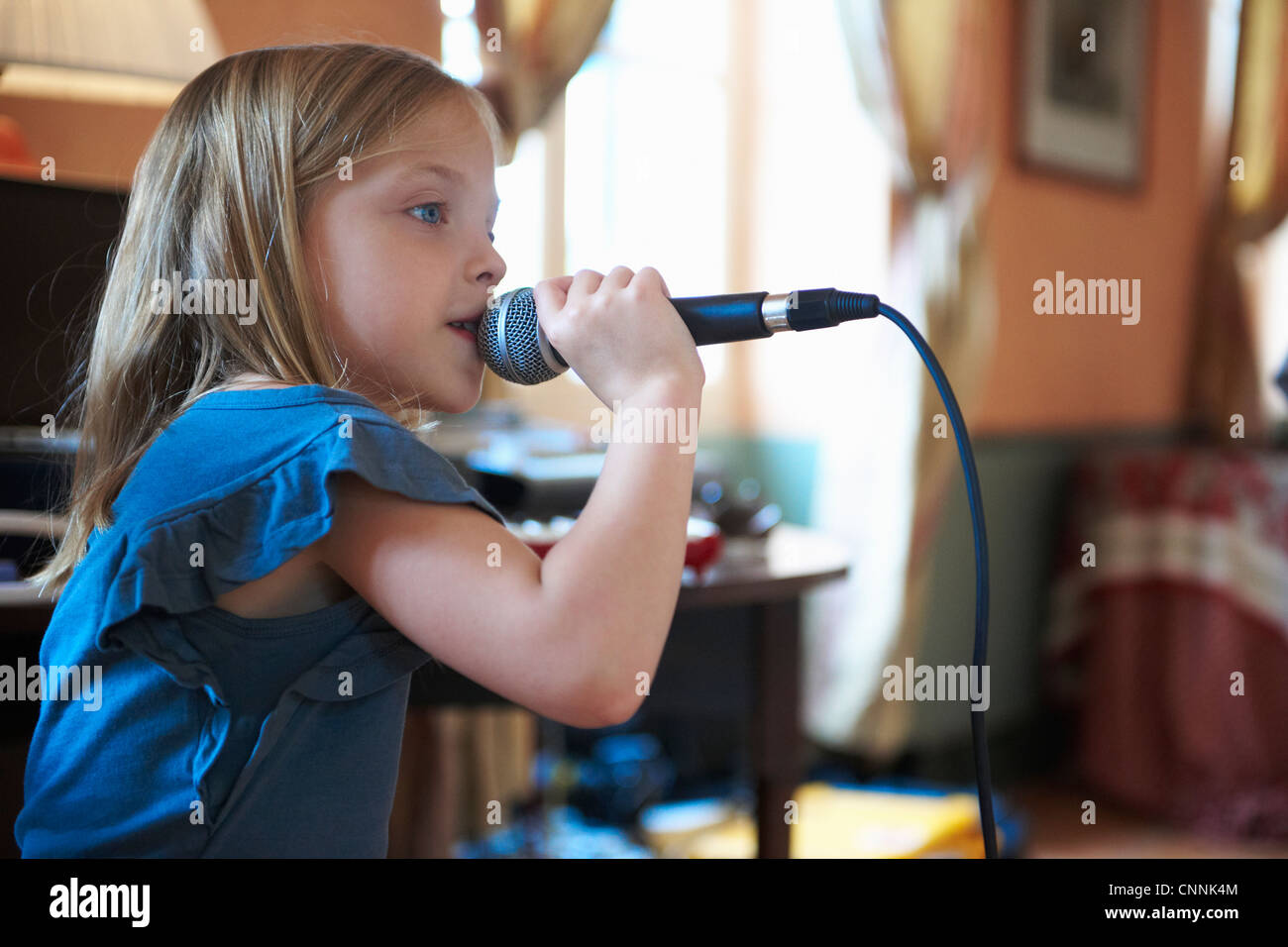 Girl singing into microphone Stock Photo - Alamy