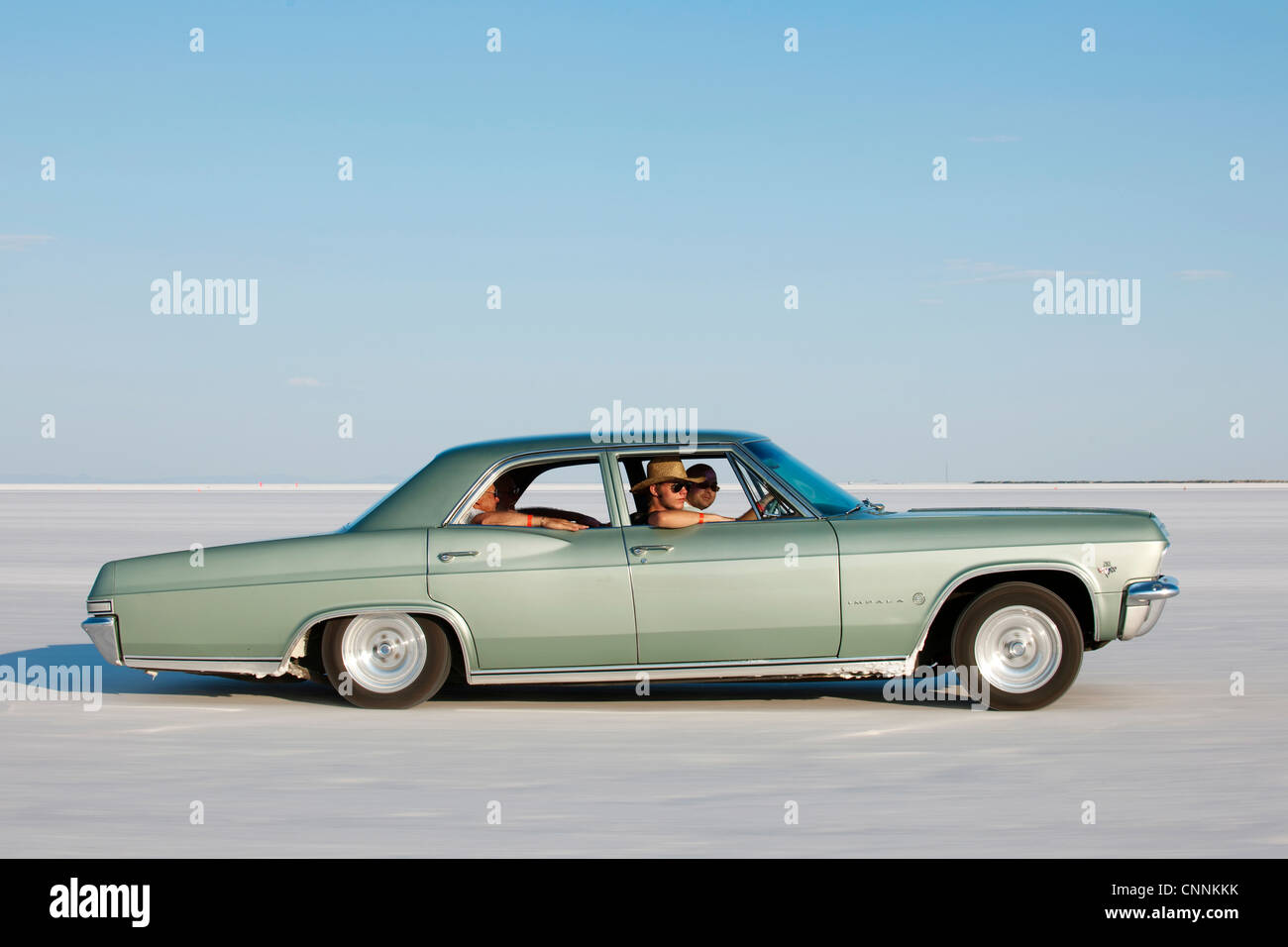 retro car driving across bonneville salt flats US blue sky white sand ...