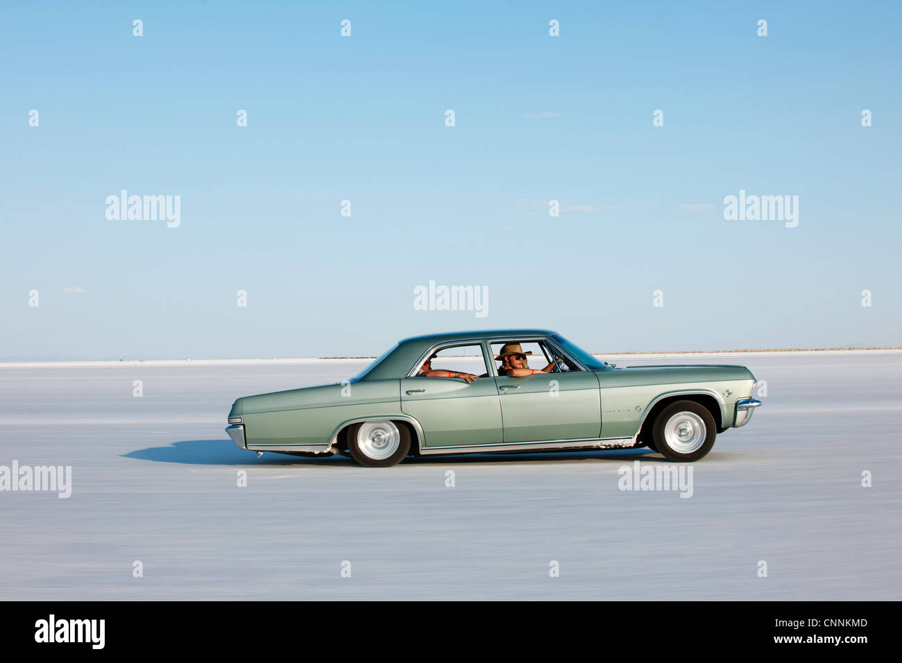 retro car driving across bonneville salt flats US blue sky white sand ...