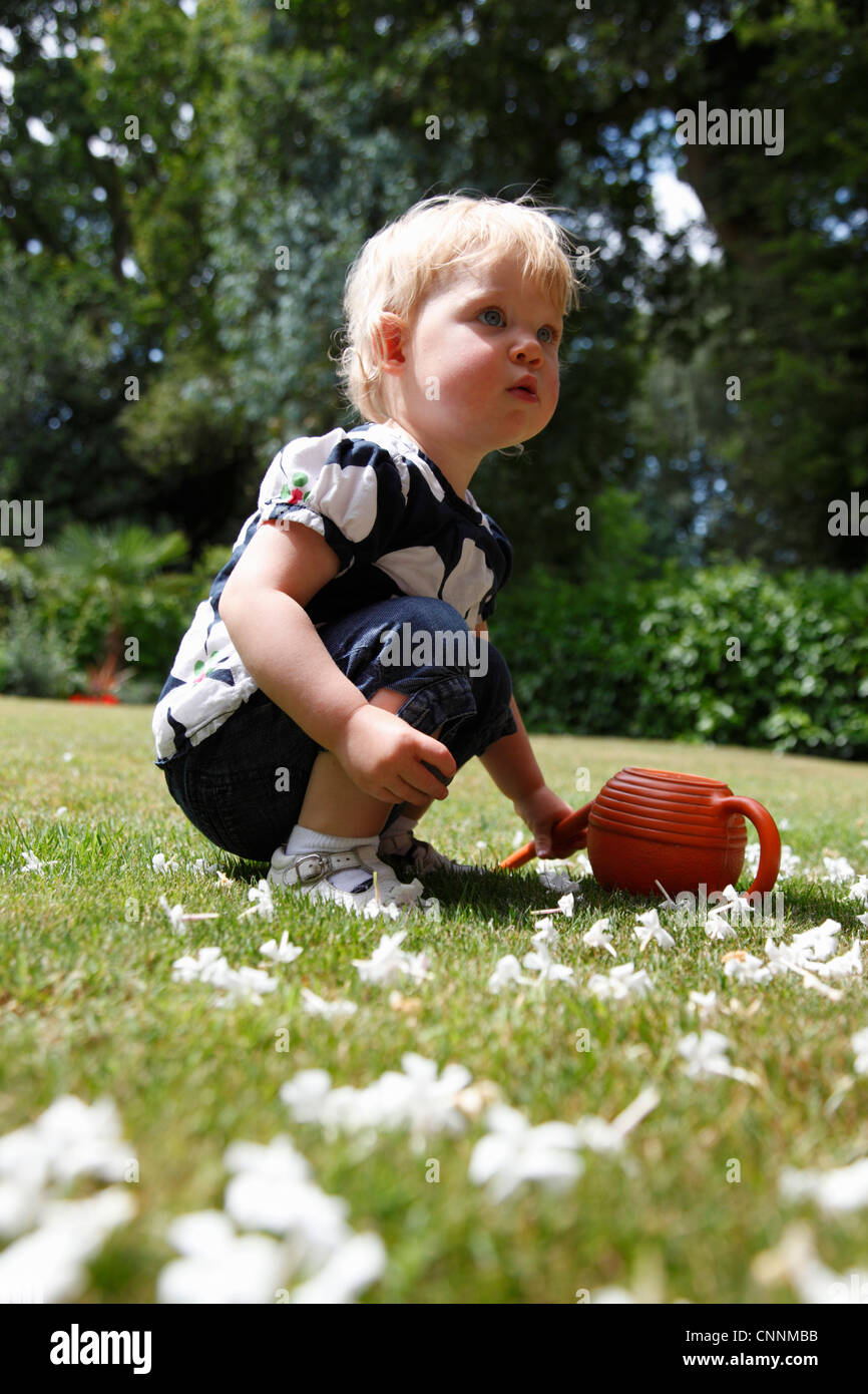 Baby Girl Crouching on Grass in Garden, Farnham, England Stock Photo ...