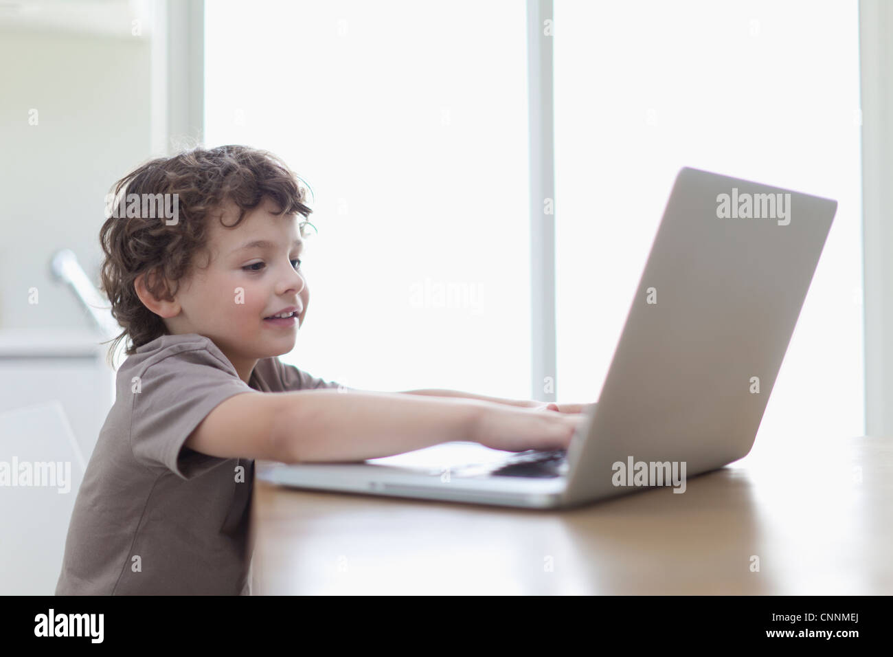 Boy using laptop at desk Stock Photo - Alamy